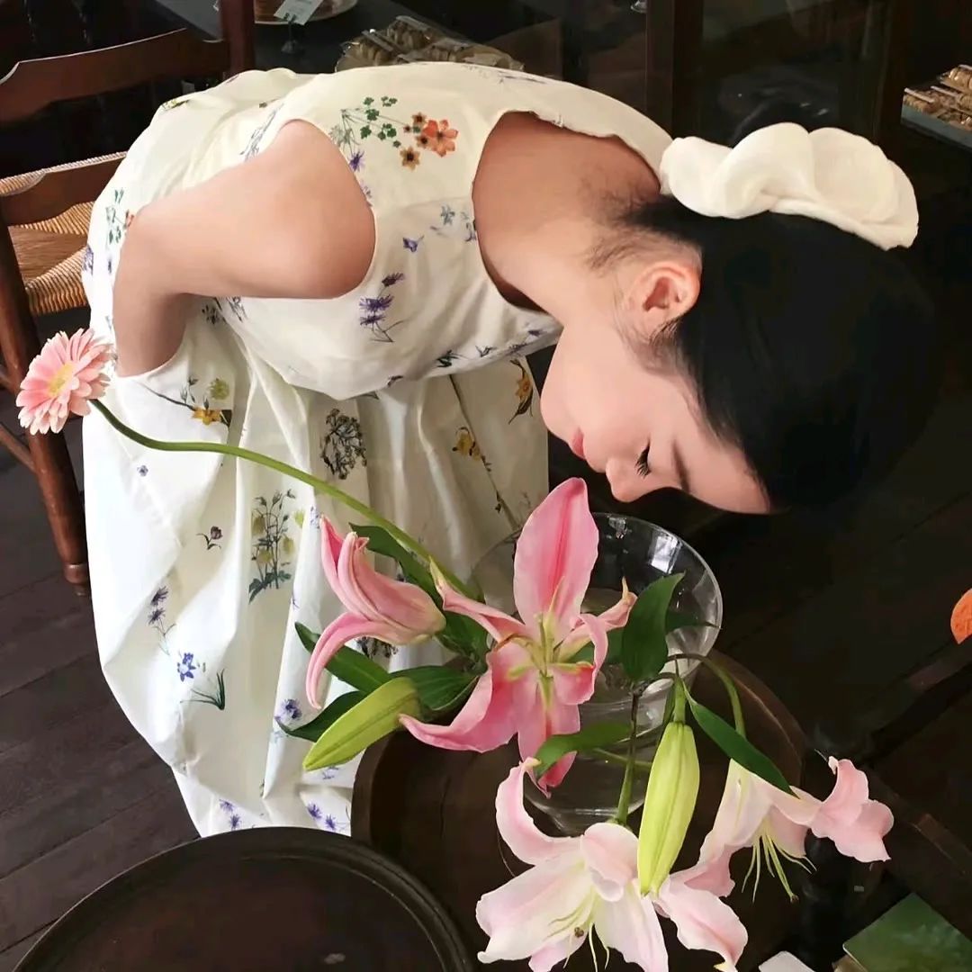 身着碎花裙的女子俯身嗅着桌上盛放的百合花，画面唯美 男女头像｜我的可爱分你一半表情包图片gif动图 - 求表情网,斗图从此不求人!